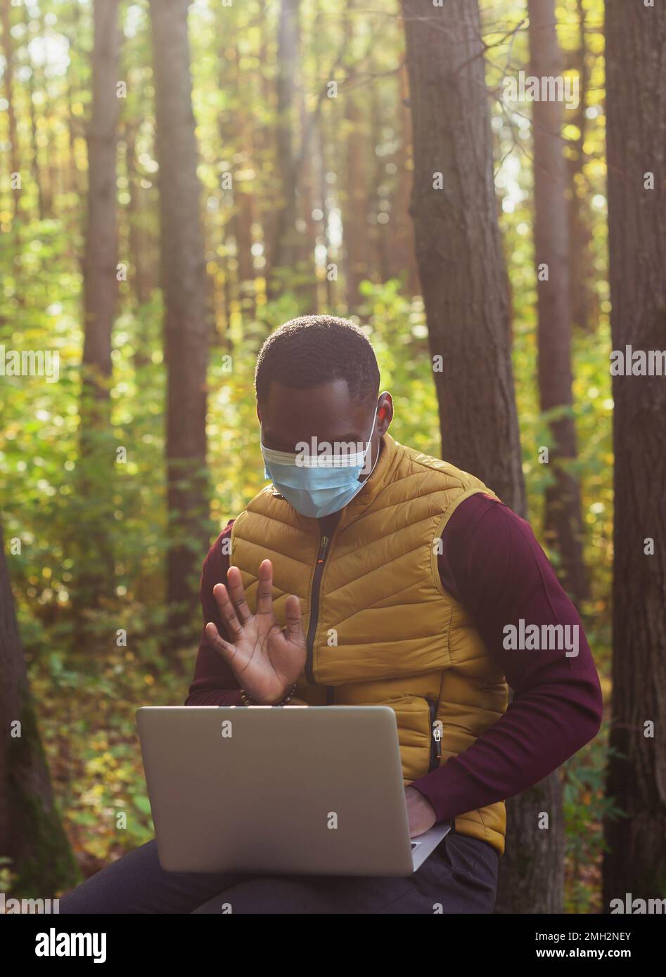 African american man in medical mask sitting in city park on a bench ...