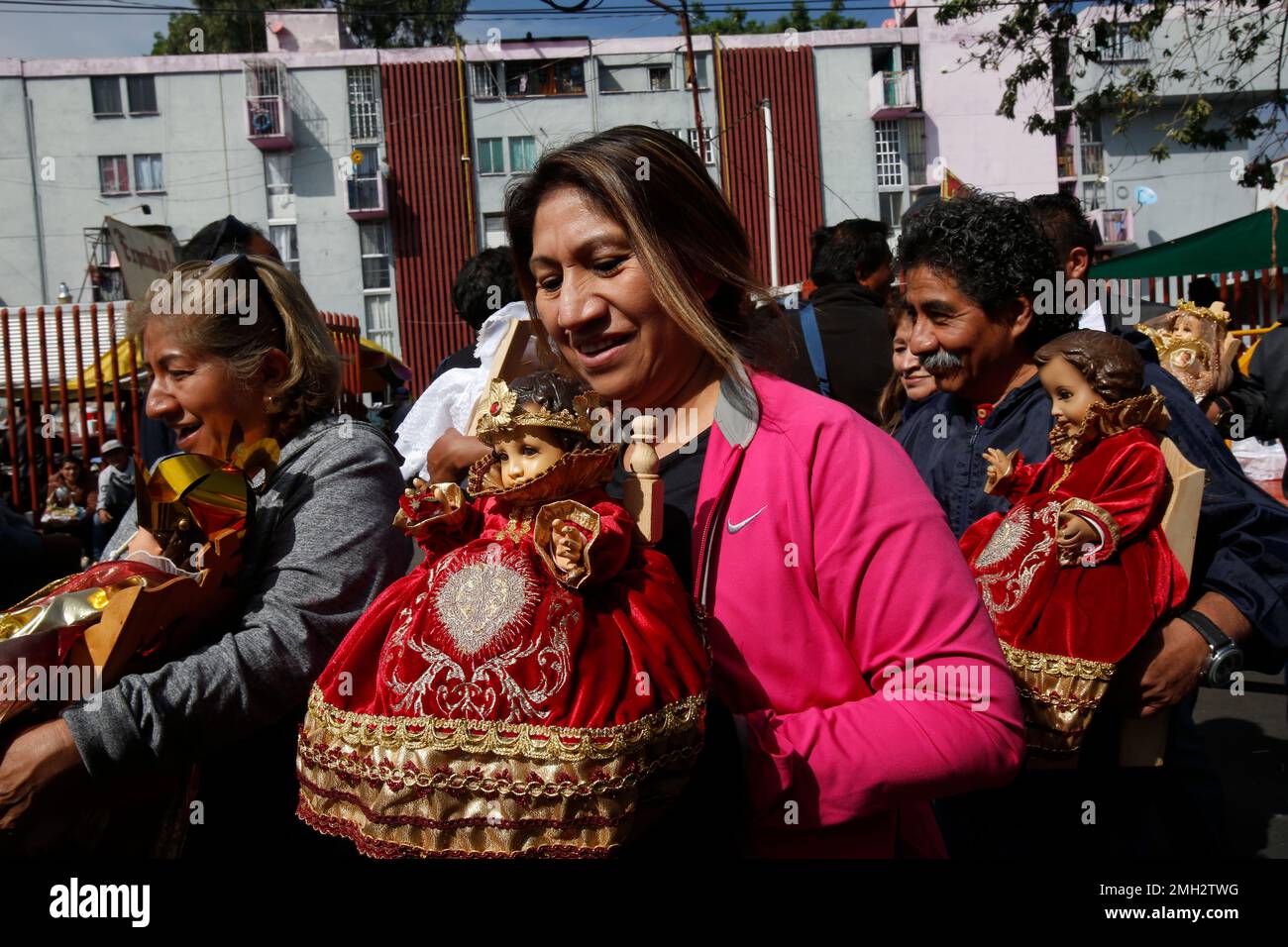 Parishioners hold their statuettes of baby Jesus to receive the priest ...
