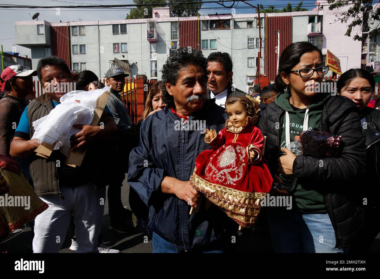 Parishioner carry their statuettes of baby Jesus to receive the priest ...