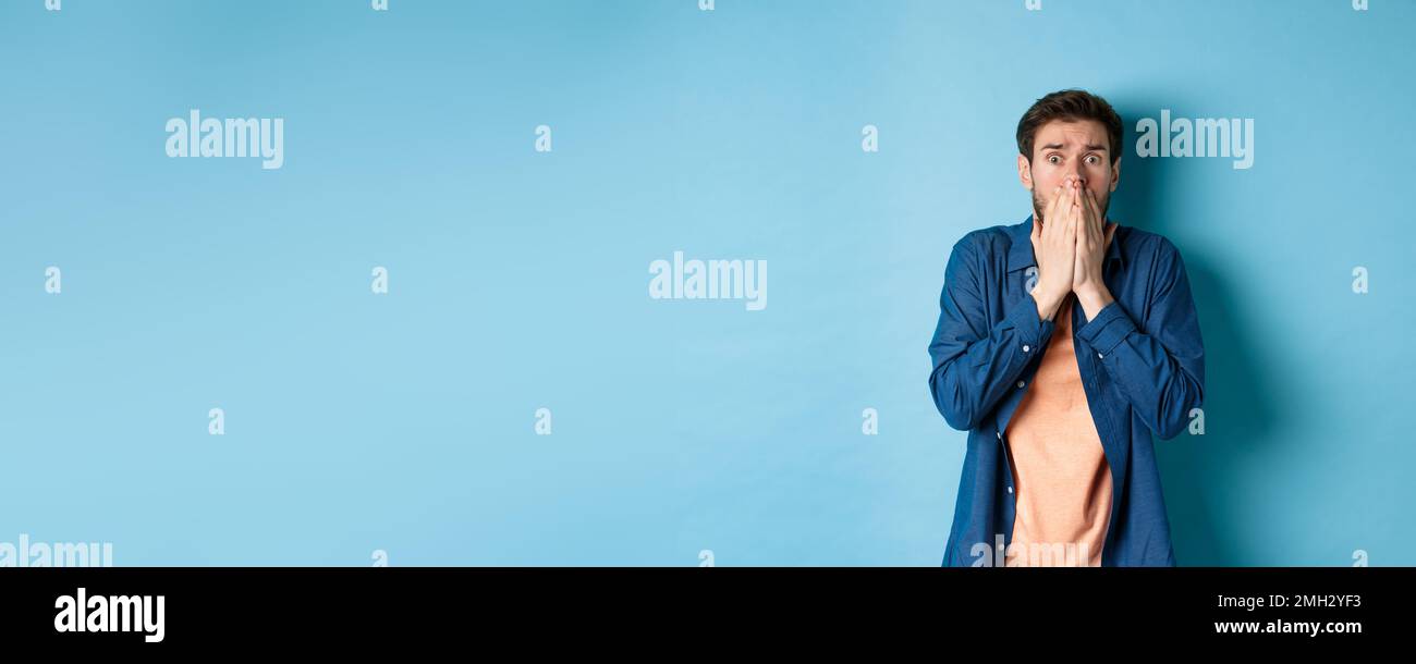 Scared anxious man covering mouth with hands and looking at something ...