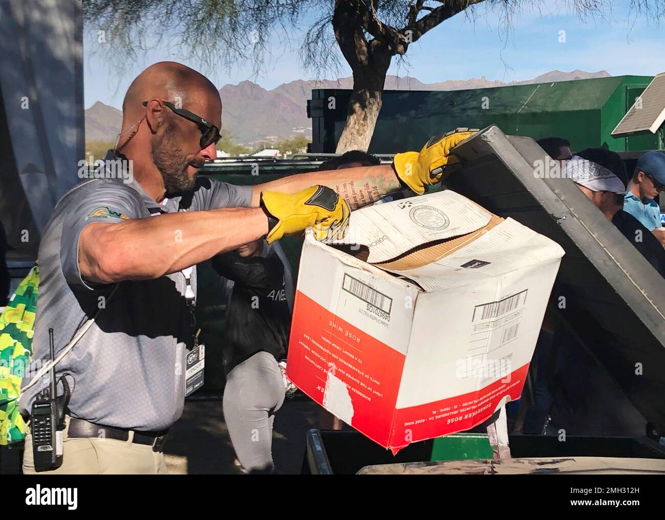 A Waste Management employee empties a box of wine bottles into a ...