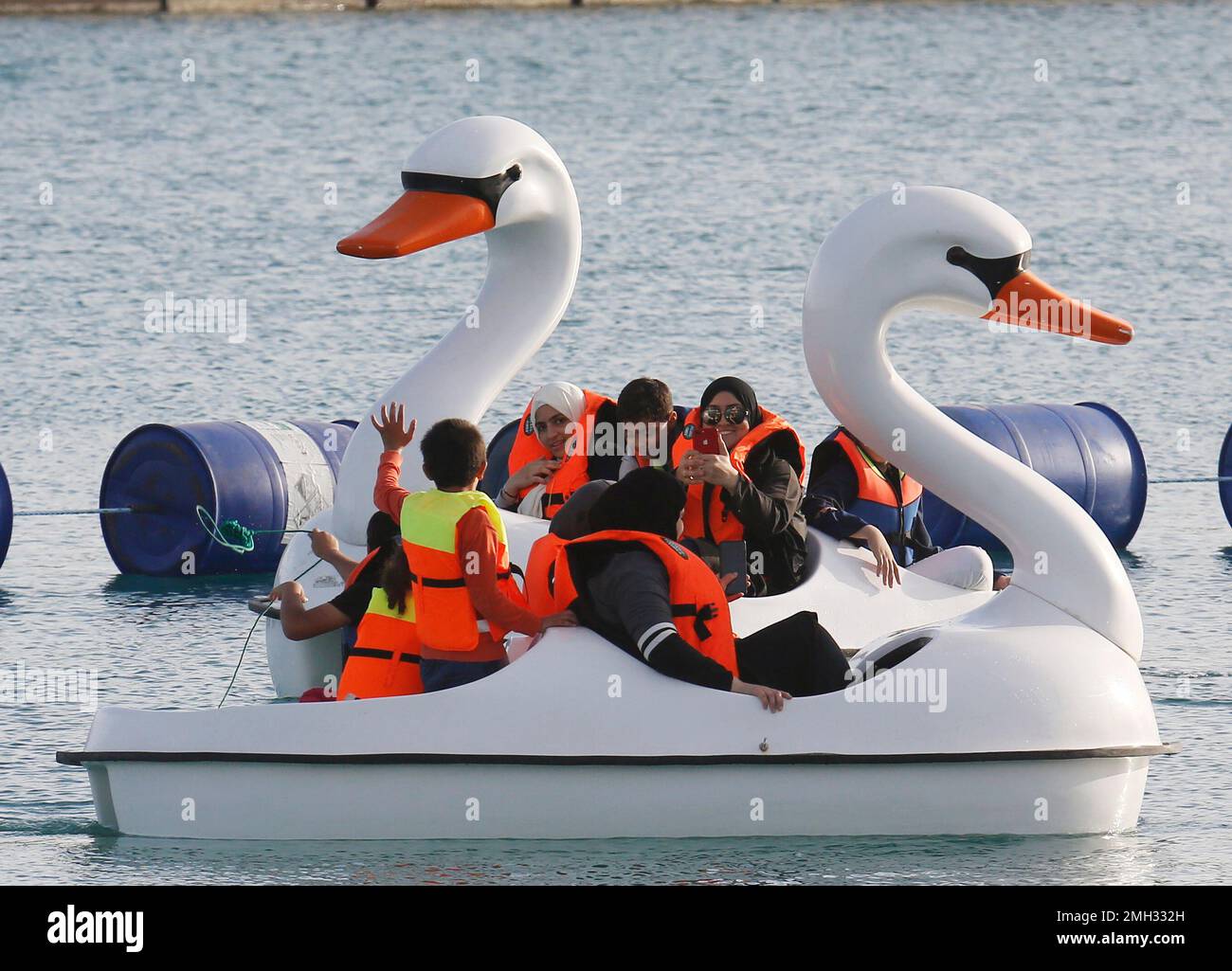 Holiday makers enjoy a swan paddle boat at the beach of the Red Sea ...