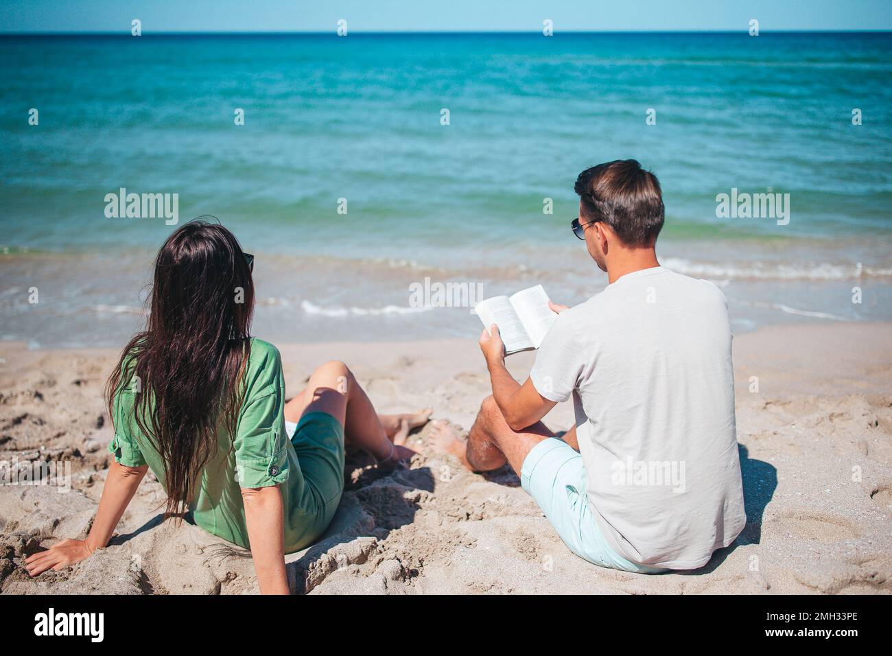 Young couple reading books on tropical beach Stock Photo - Alamy