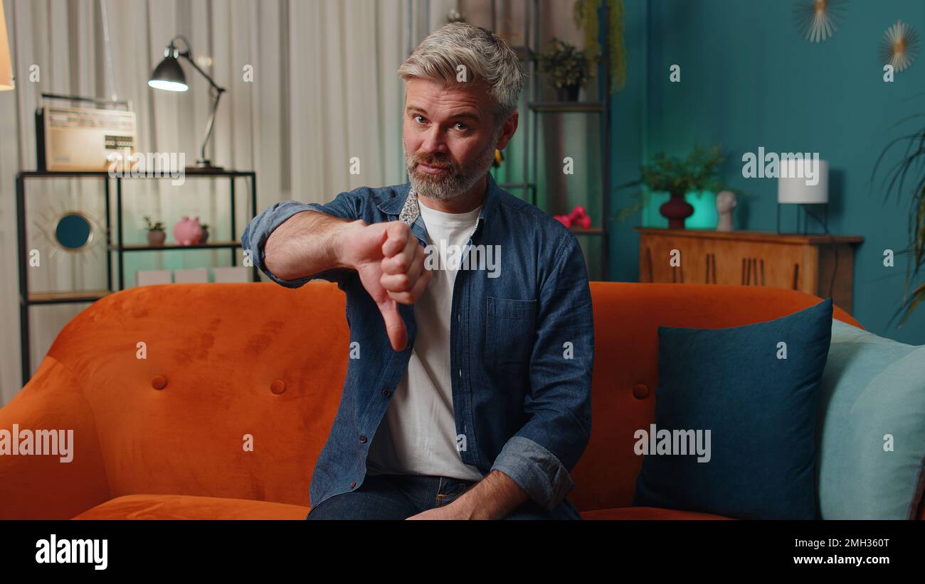 Dislike. Upset middle-aged man showing thumbs down sign gesture ...