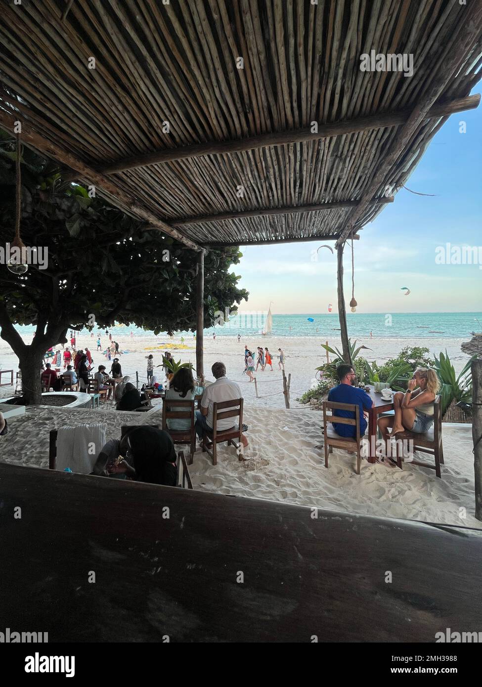View of a resort beach with some kites and tables for a restaurant in ...