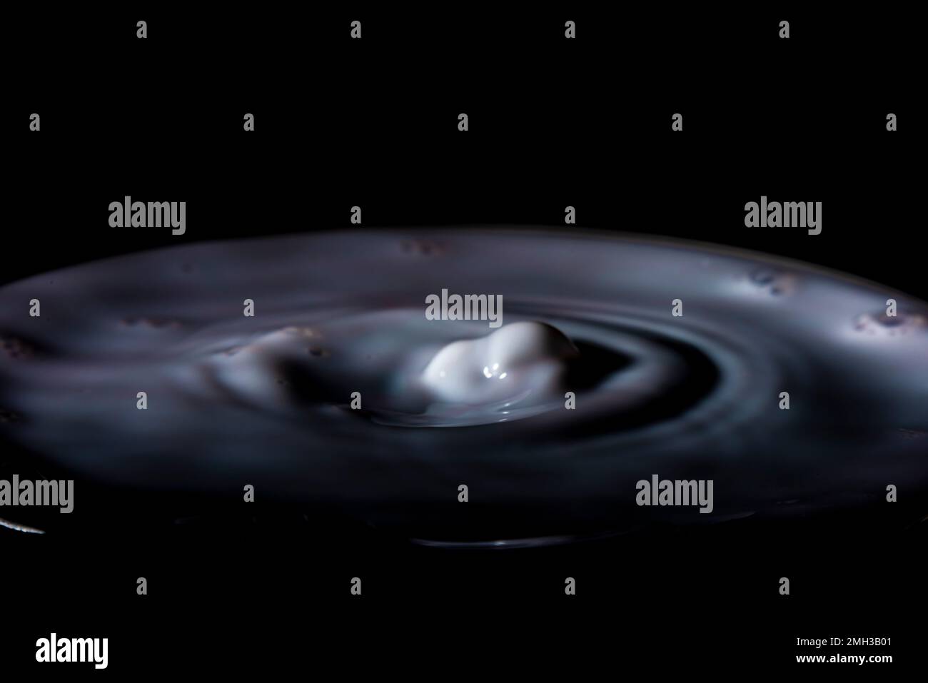 Color fresh sweet milk drops into another color of milk in cup with ...