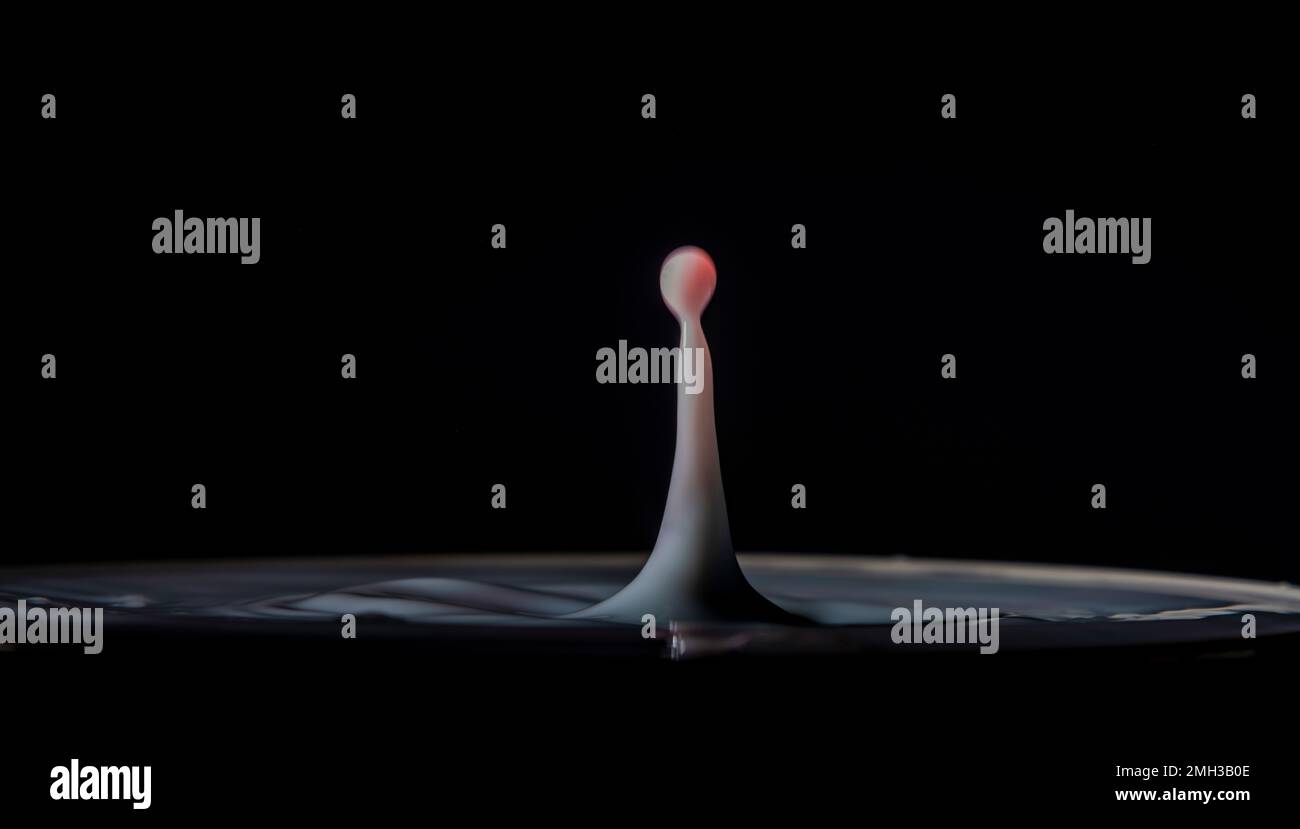 Color fresh sweet milk drops into another color of milk in cup with ...