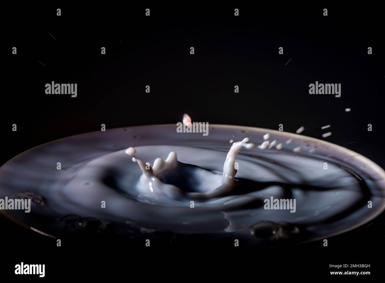 Color fresh sweet milk drops into another color of milk in cup with ...