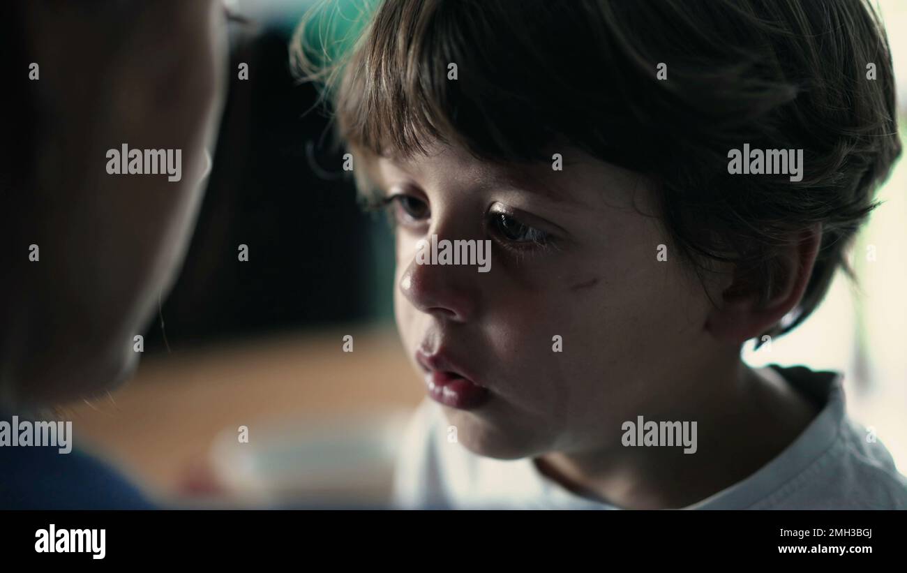 Candid tearful small boy listening to mother scold him for misbehaving ...