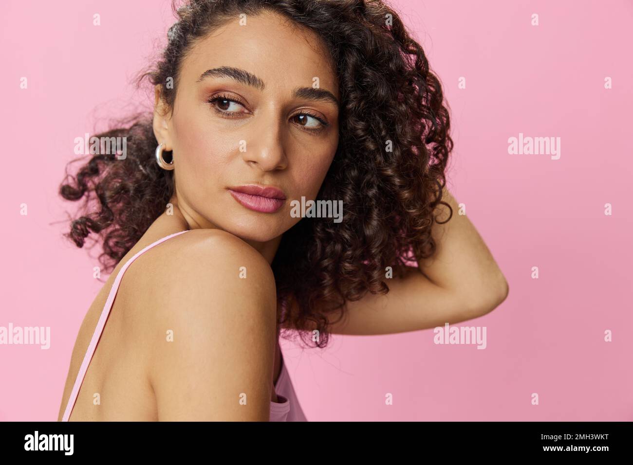 Woman with curly afro hair model poses on a pink background in a pink T ...