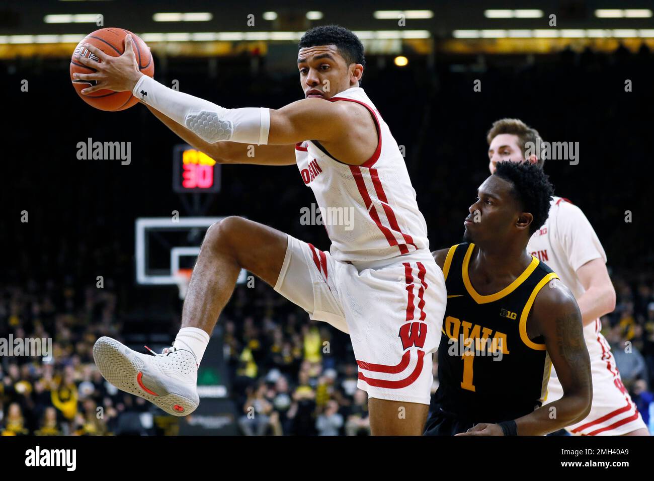 Wisconsin guard D'Mitrik Trice grabs a rebound over Iowa guard Joe ...