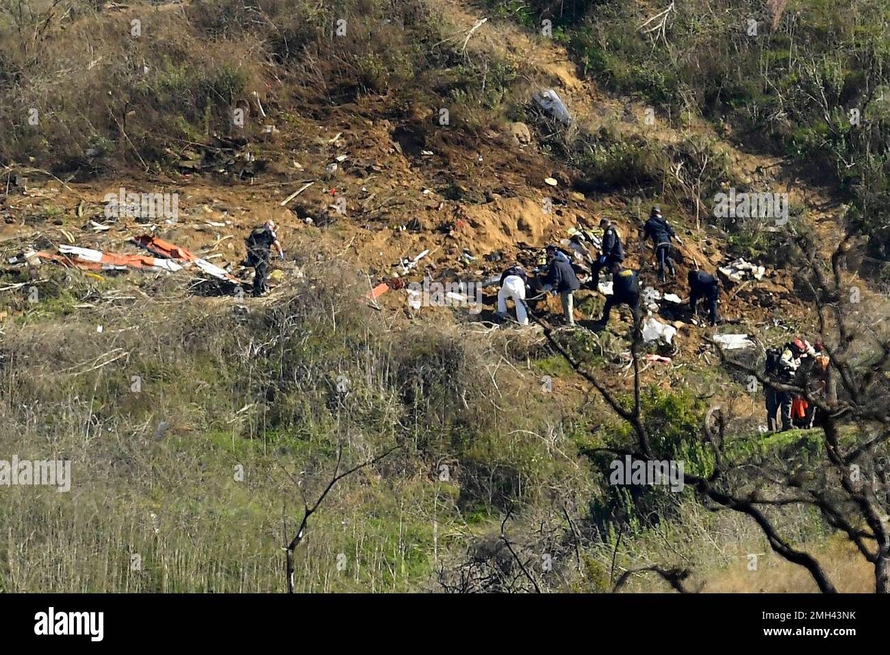 Investigators work the scene of a helicopter crash that killed former ...