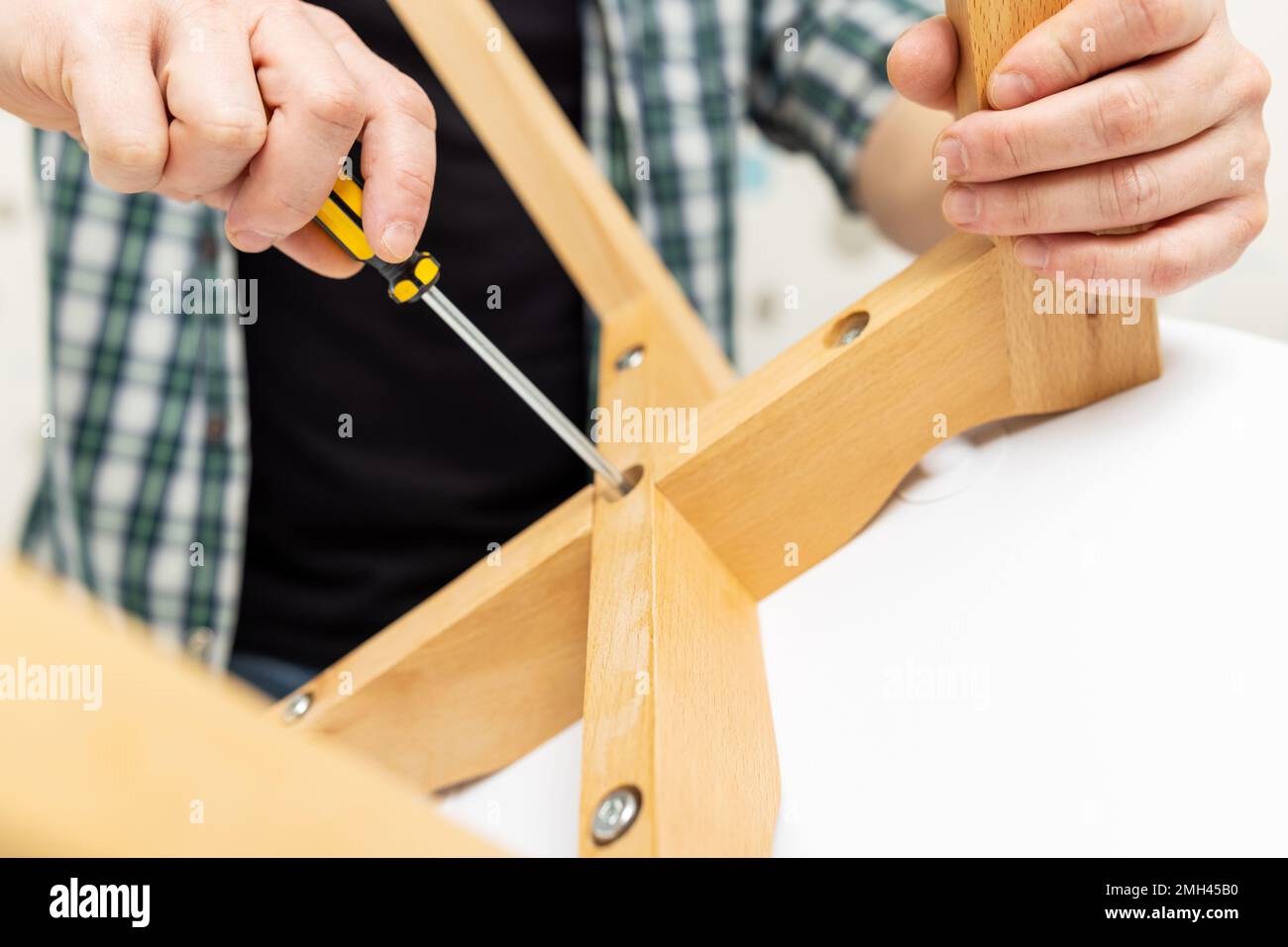 Self-assembly furniture concept. The young man himself assembling ...
