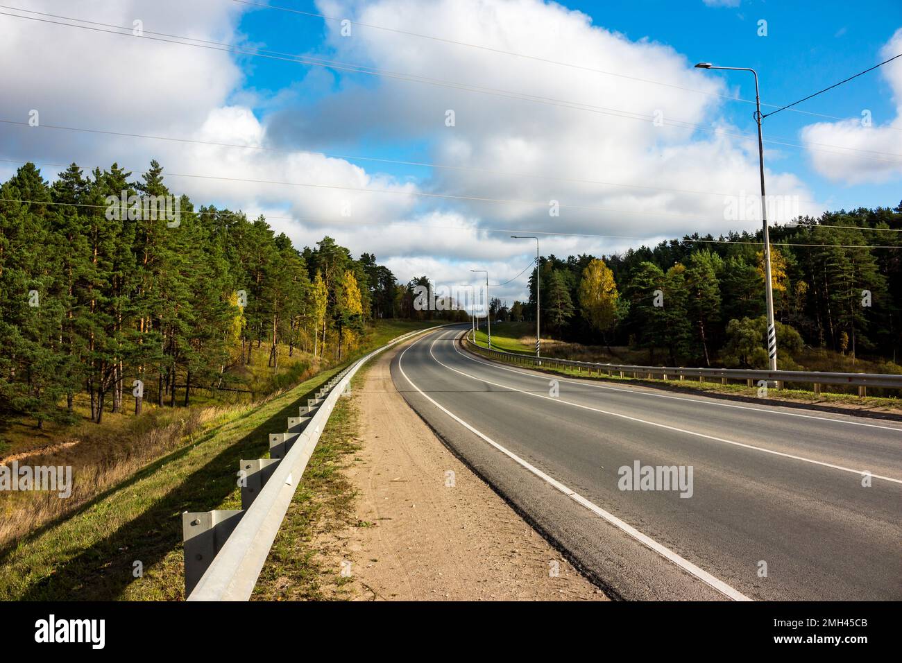 Smooth curve of a turning empty car road surrounded by pines landscape ...