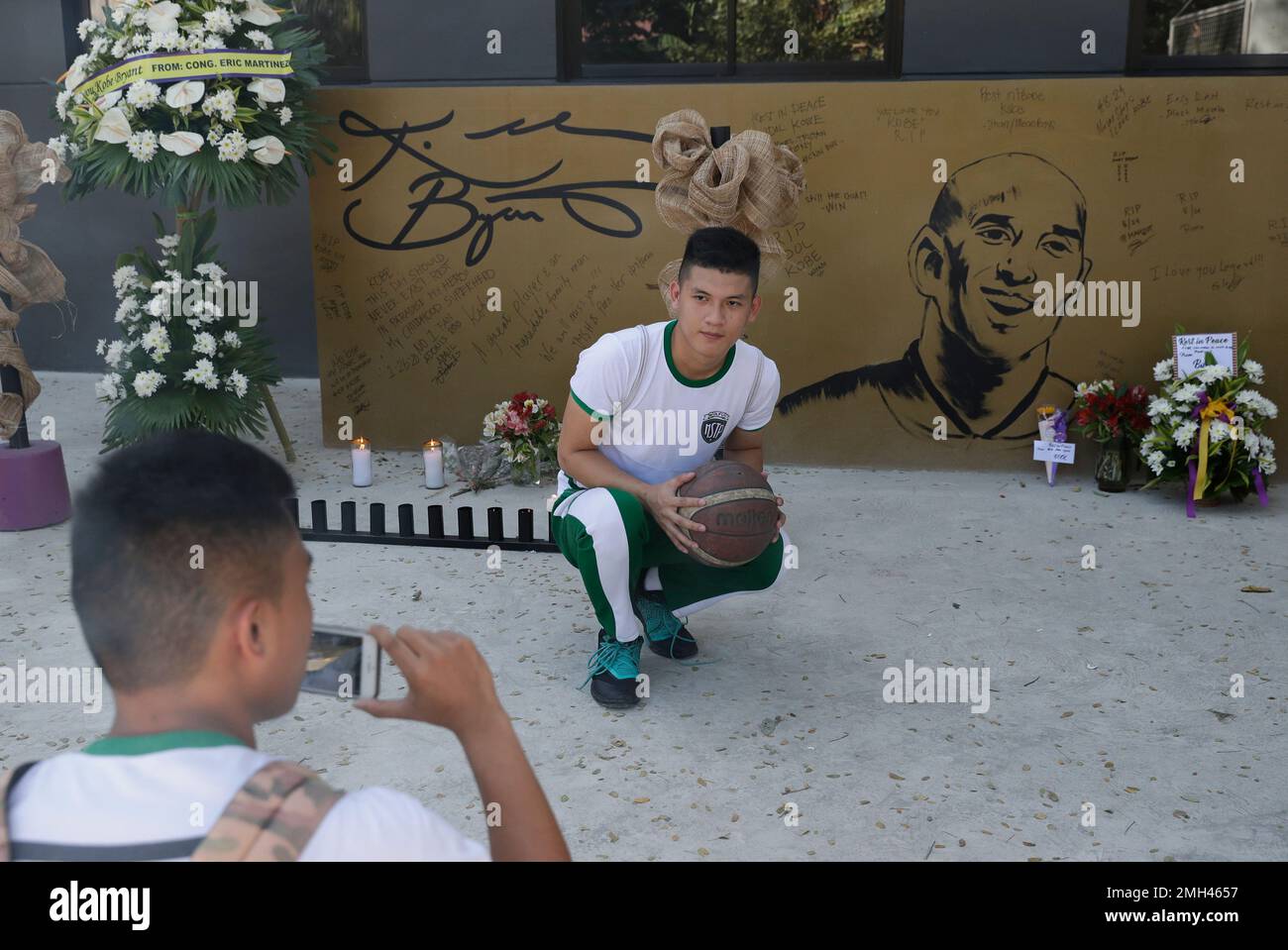 Students pose beside a sketch of former NBA basketball player Kobe ...