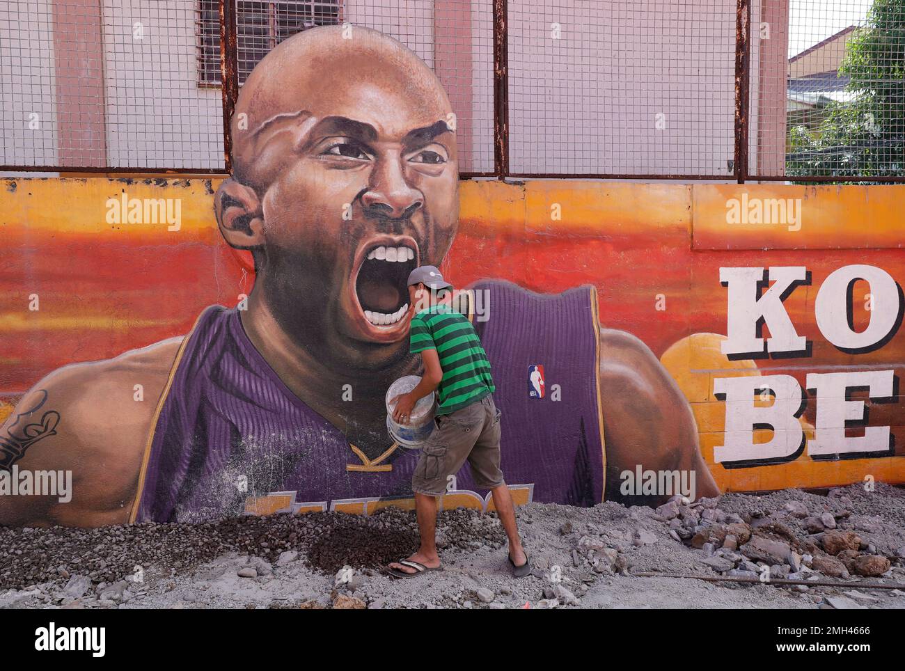 A man work beside a painting of former NBA basketball player Kobe ...