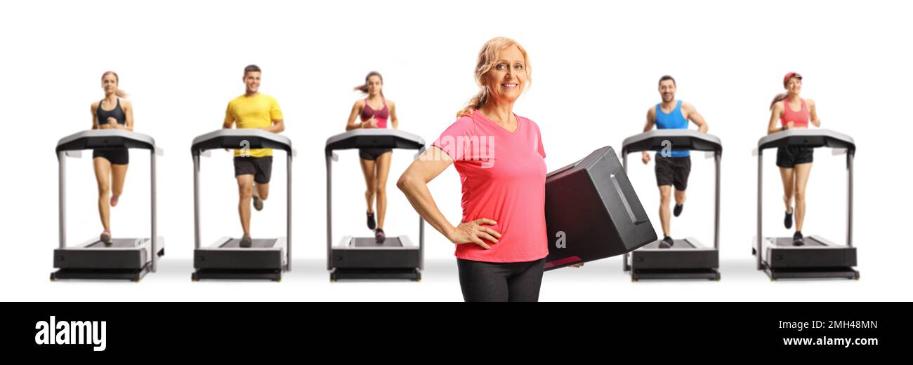 Woman holding a step aerobic platform and people running on treadmills ...