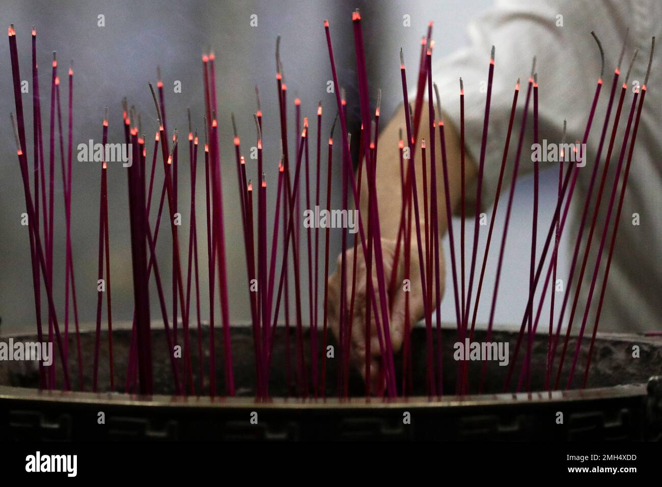 A man places incense sticks on a vase at the Seng Guan temple at Manila ...