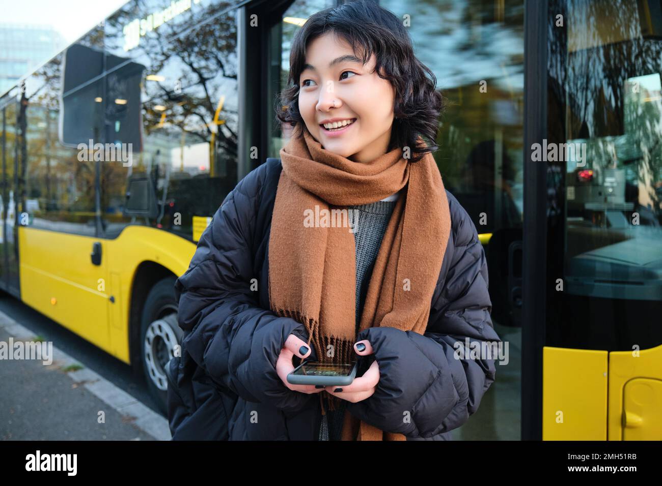 Young beautiful woman standing on bus stop, texting message on ...