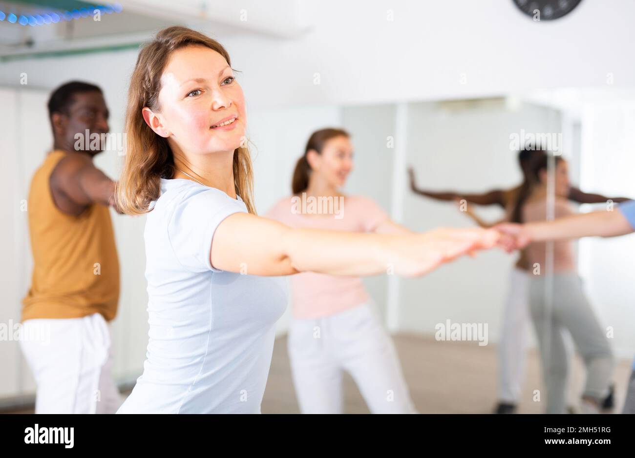 Smiling young adult couples dancing together in pairs and practicing ...
