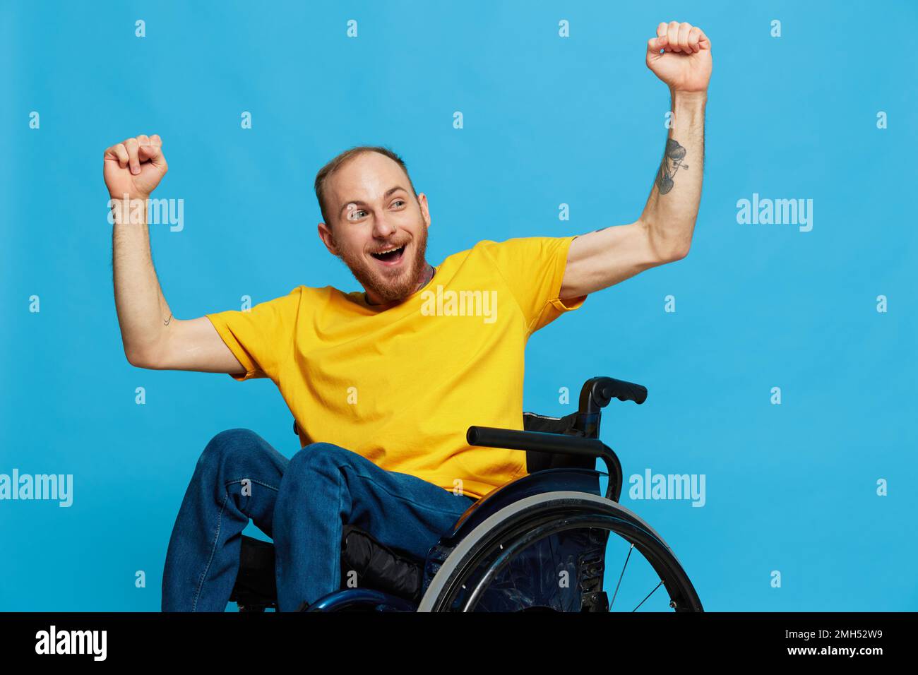 A man in a wheelchair happiness raised his hands up in a t-shirt with ...