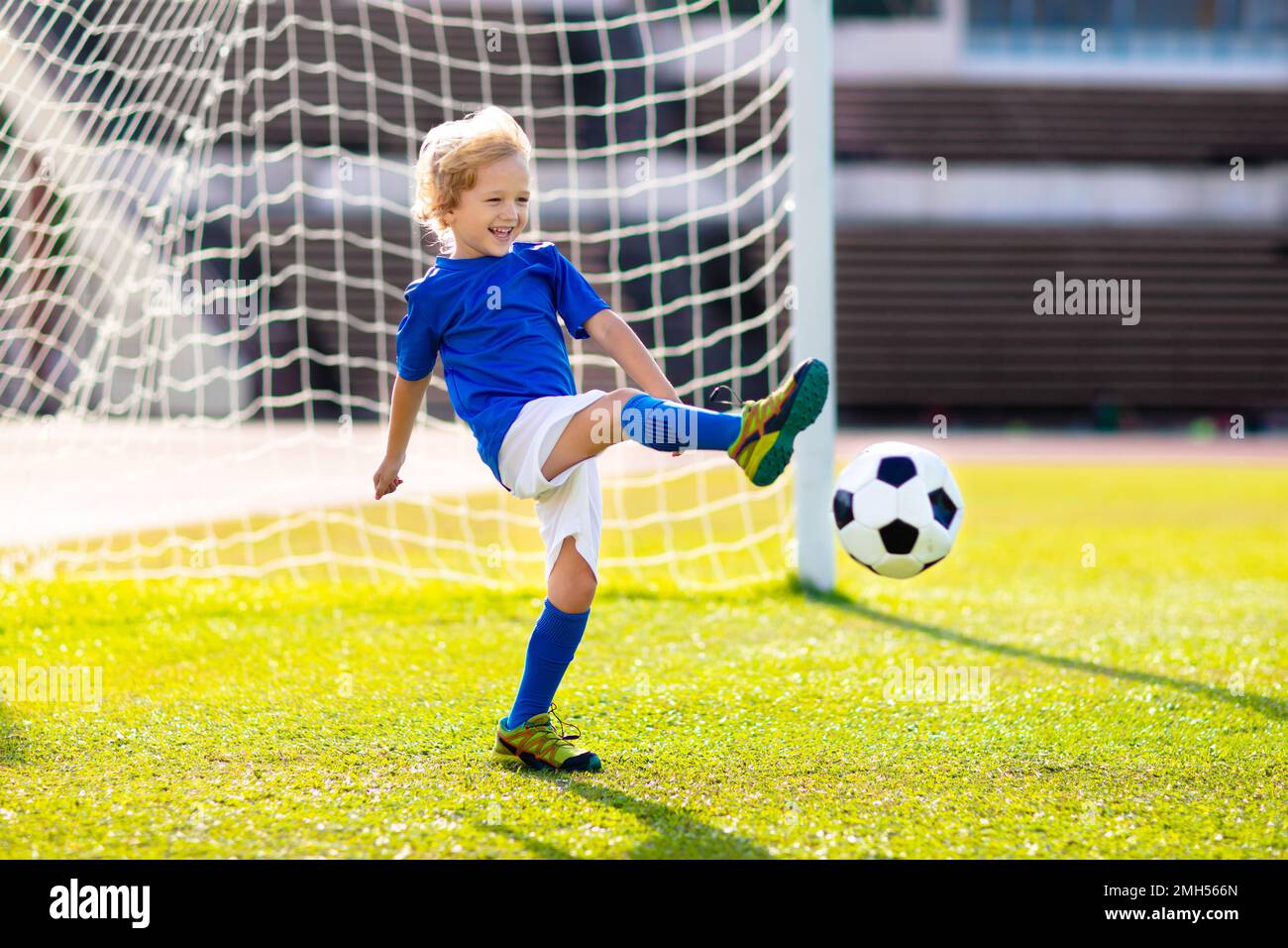 Kids play football on outdoor stadium field. Children score a goal ...