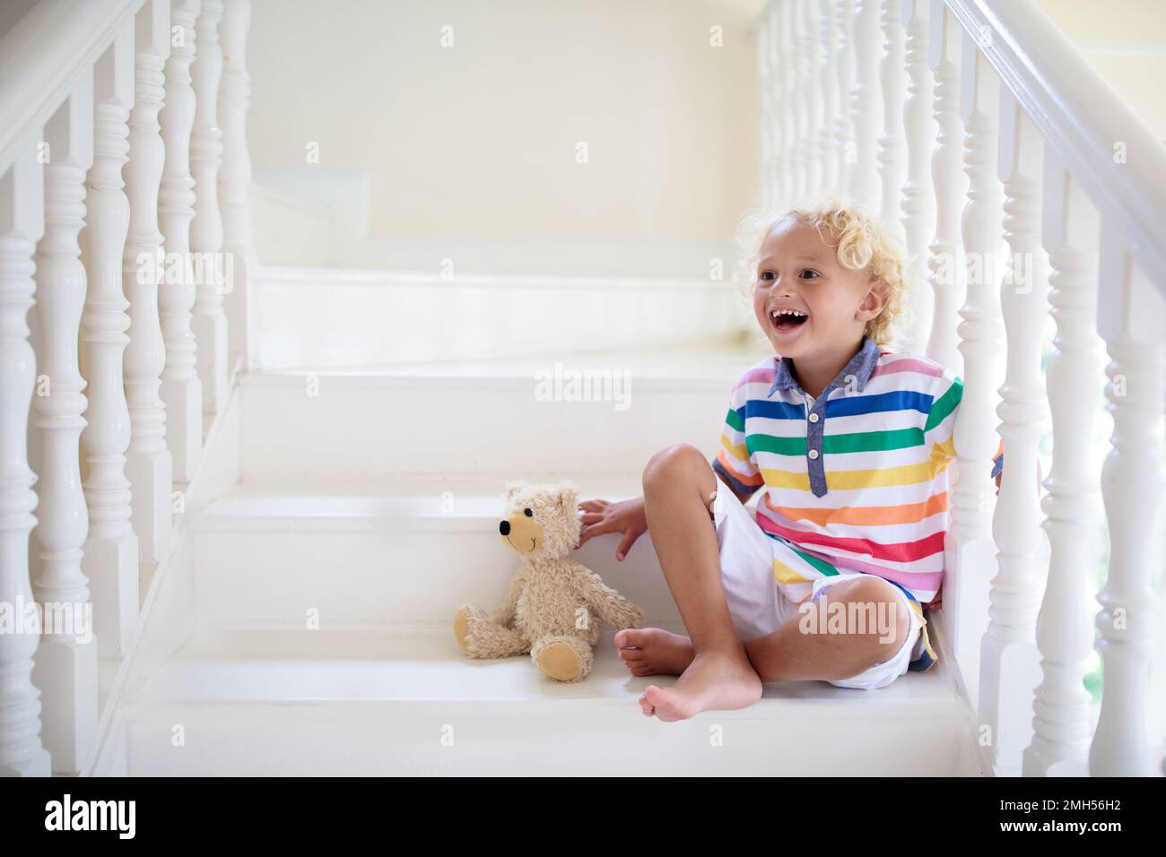 Kid walking stairs in white house. Little boy playing in sunny ...