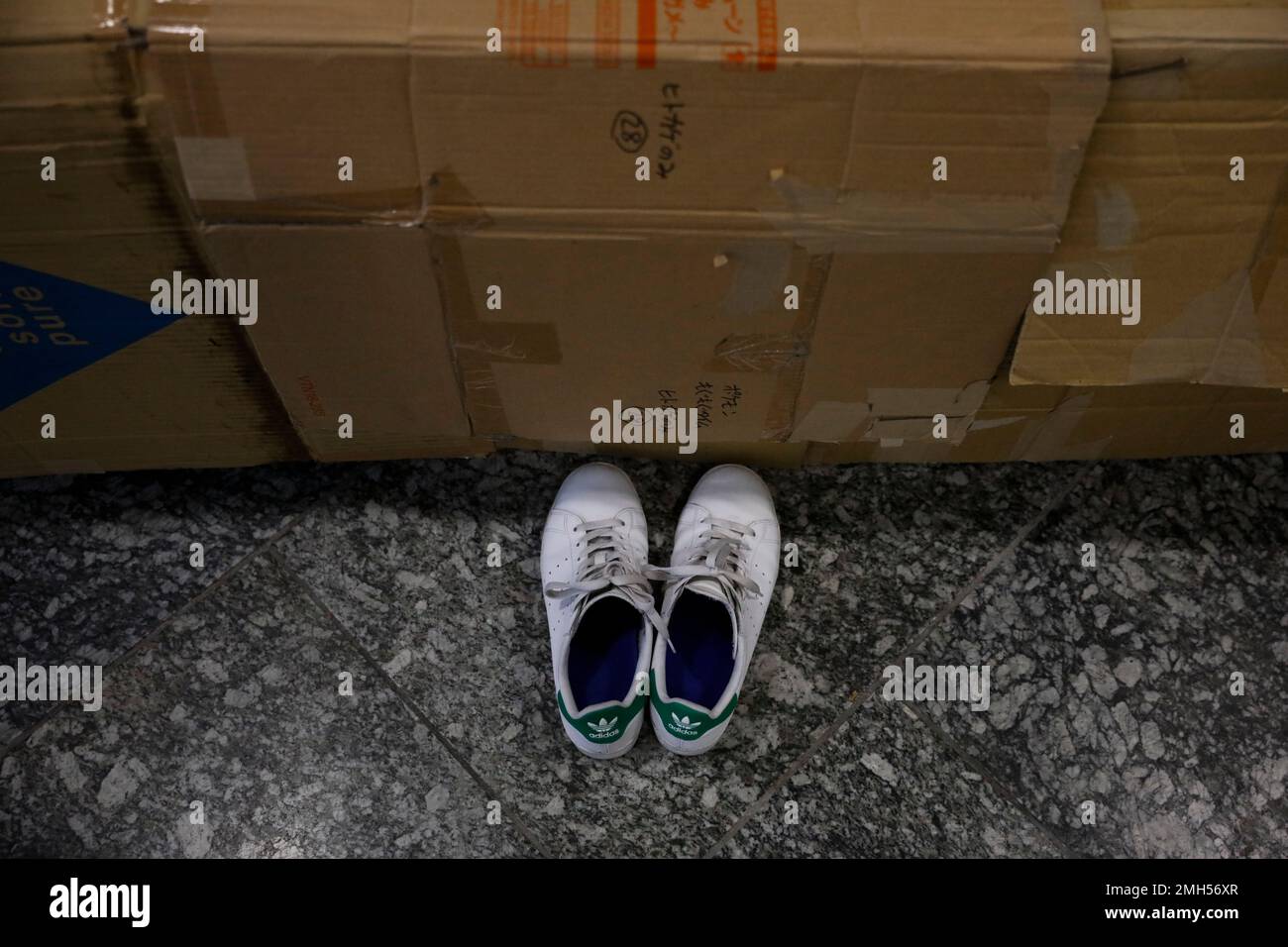 Homeless person's shoes are placed in front of a cardboard box at ...