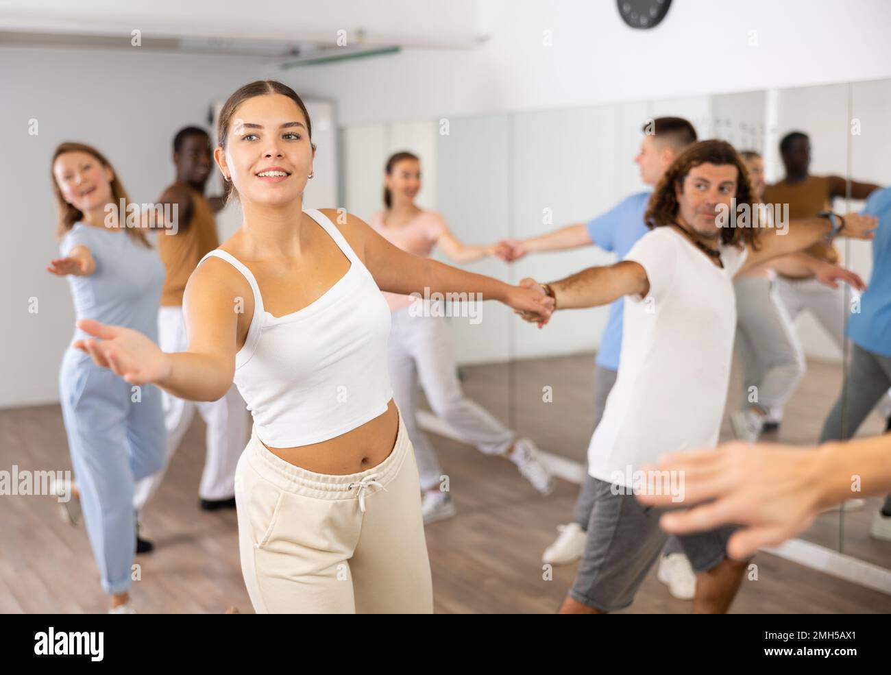 Smiling young adult couples dancing together in pairs and practicing ...