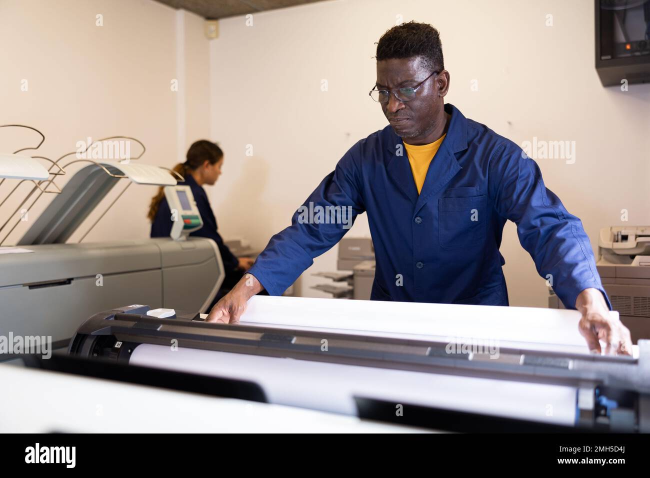 Focused African American male in a blue robe uniform using plotter ...