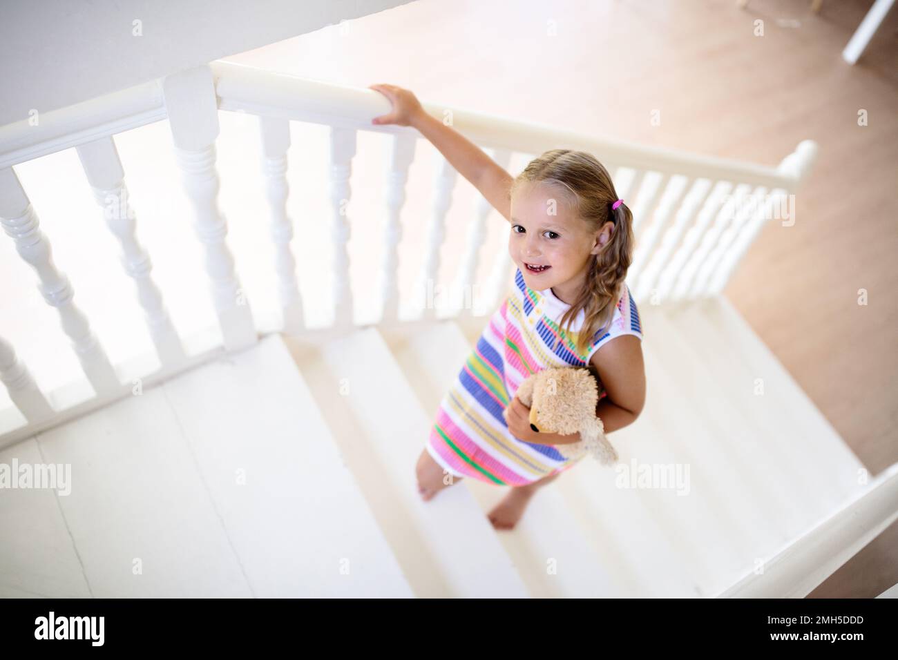 Kid walking stairs in white house. Little girl playing in sunny ...
