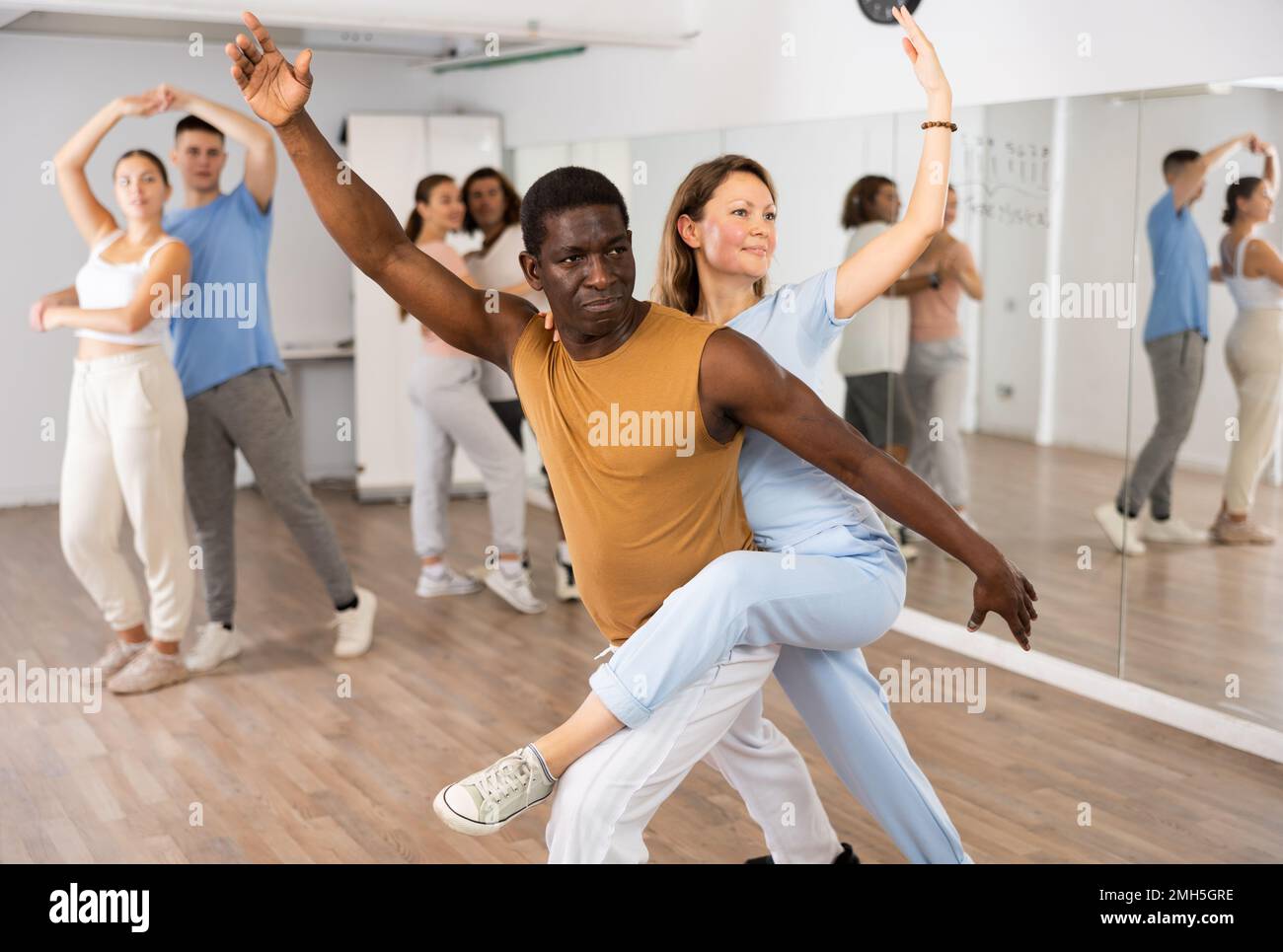 Group of excited young adult people dancing dynamic moves in pairs ...