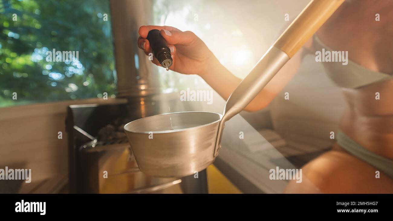 Hand dripping essential aromatic oil from a dropper bottle in to water ...