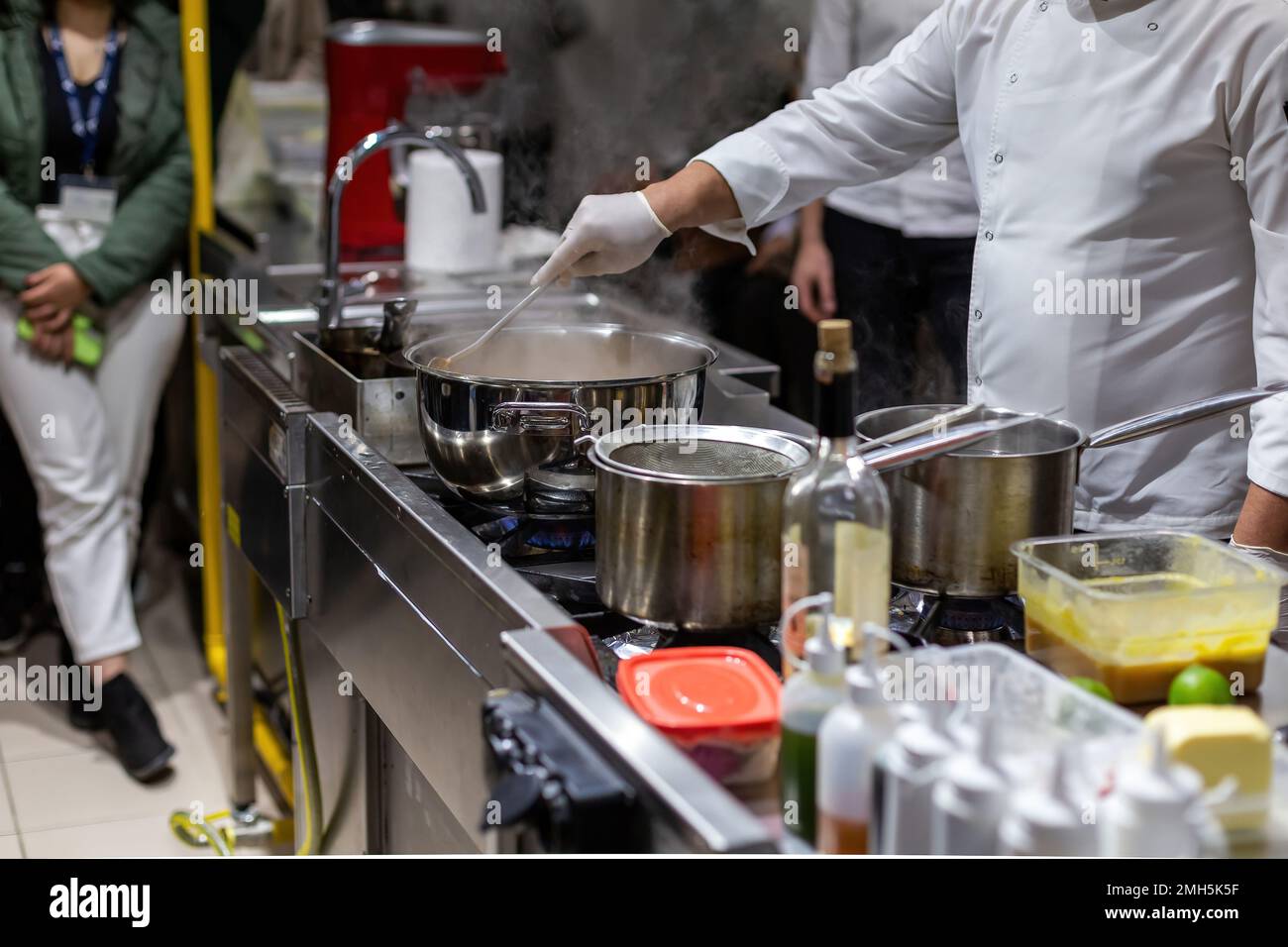 A cook stirring pots in the kitchen. Big pots in the kitchen Stock ...