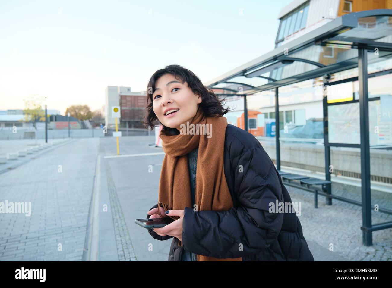 Cute young girl, student waiting on a bus stop, looking for her public ...