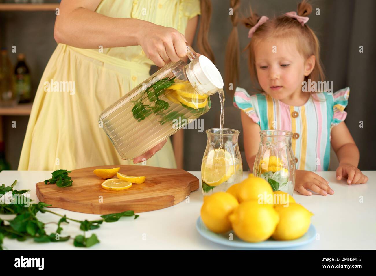 mother pours lemonade for daughter. family makes lemonade together in ...