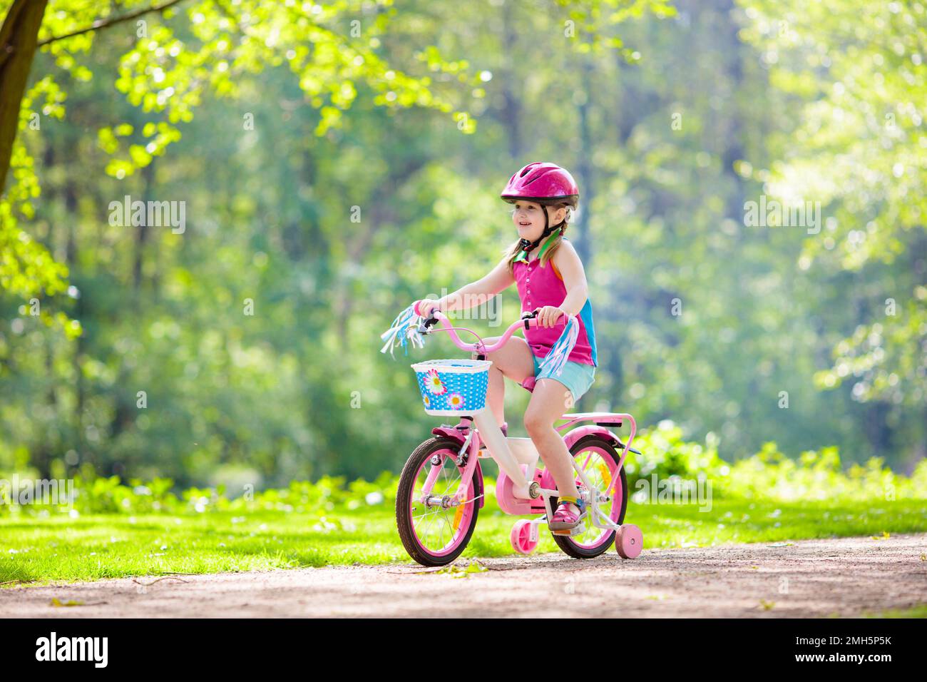 Child riding bike. Kid on bicycle in sunny park. Little girl enjoying ...