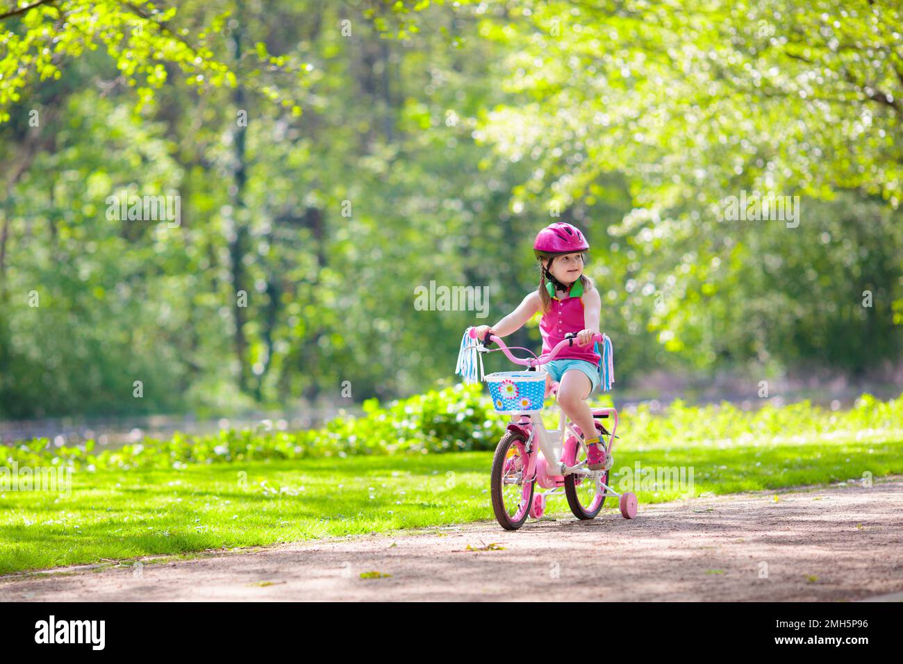 Child riding bike. Kid on bicycle in sunny park. Little girl enjoying ...
