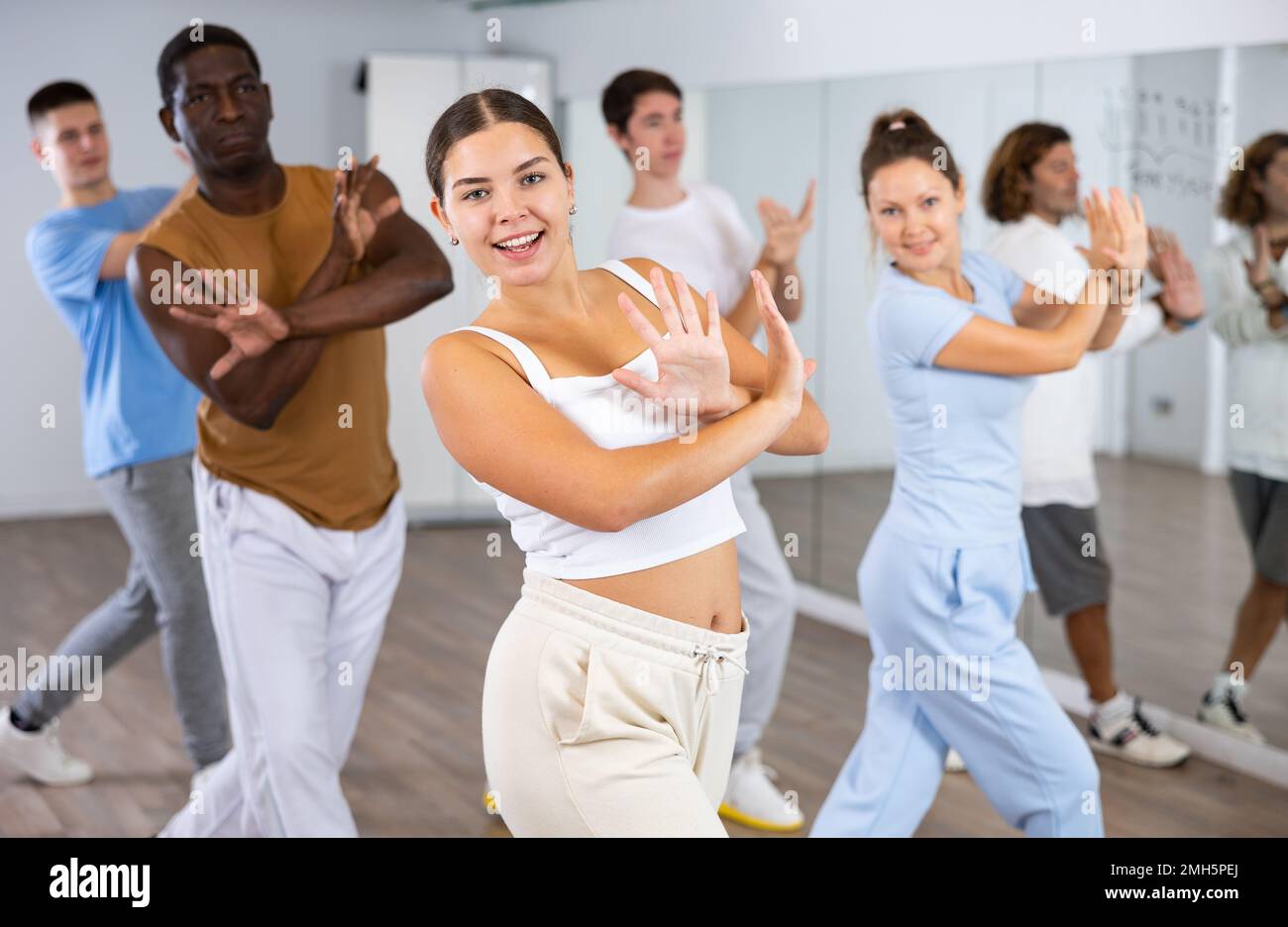 Group of young adult diverse active dancers in sportswear with crossed ...