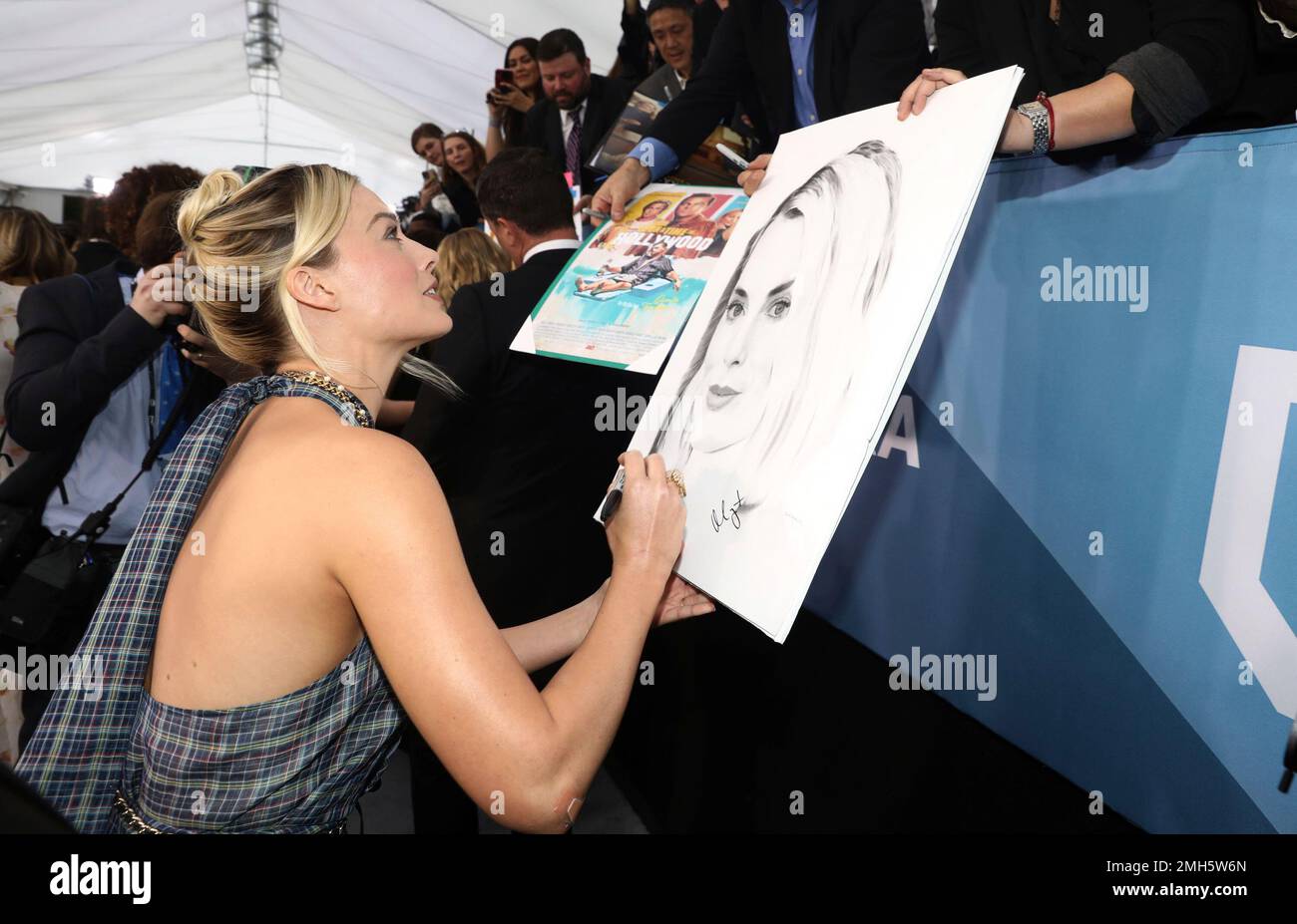 Margot Robbie signs an autograph as she arrives at the 26th annual ...