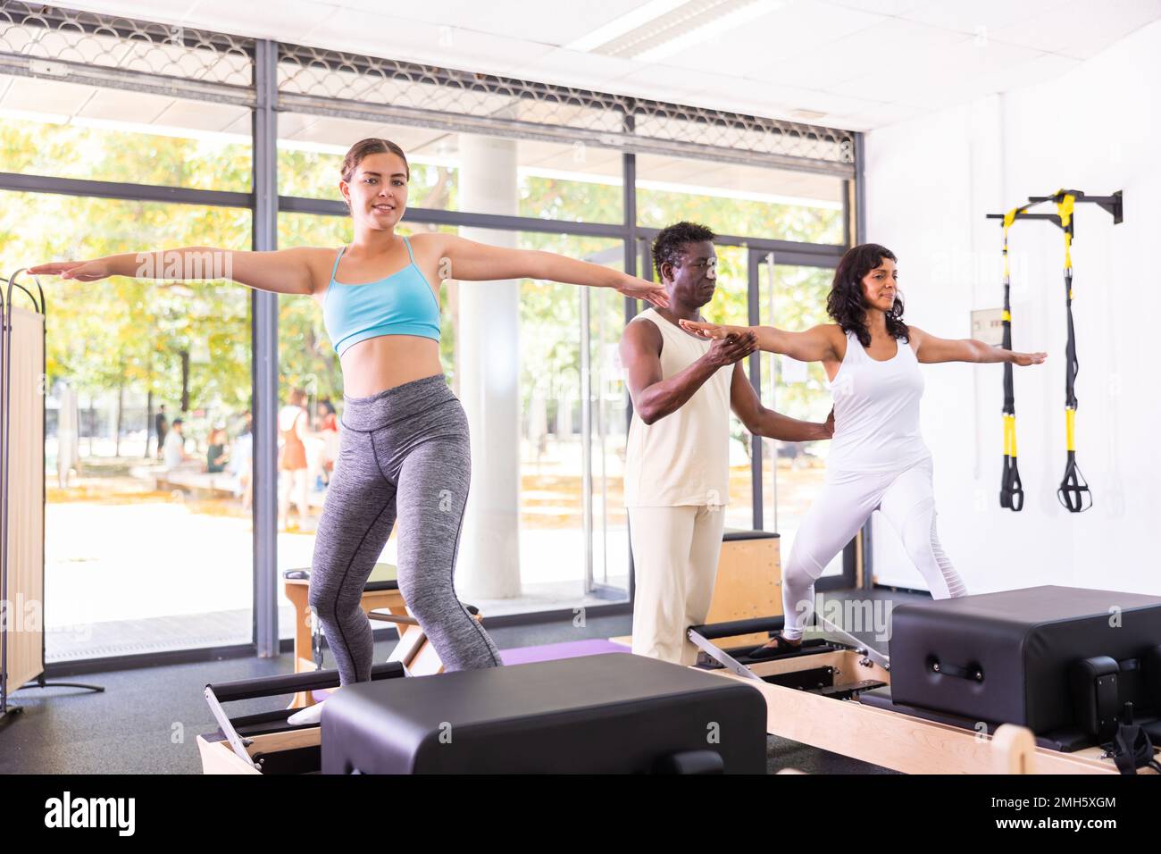 Female pilates trainer helping pilates people during training Stock ...