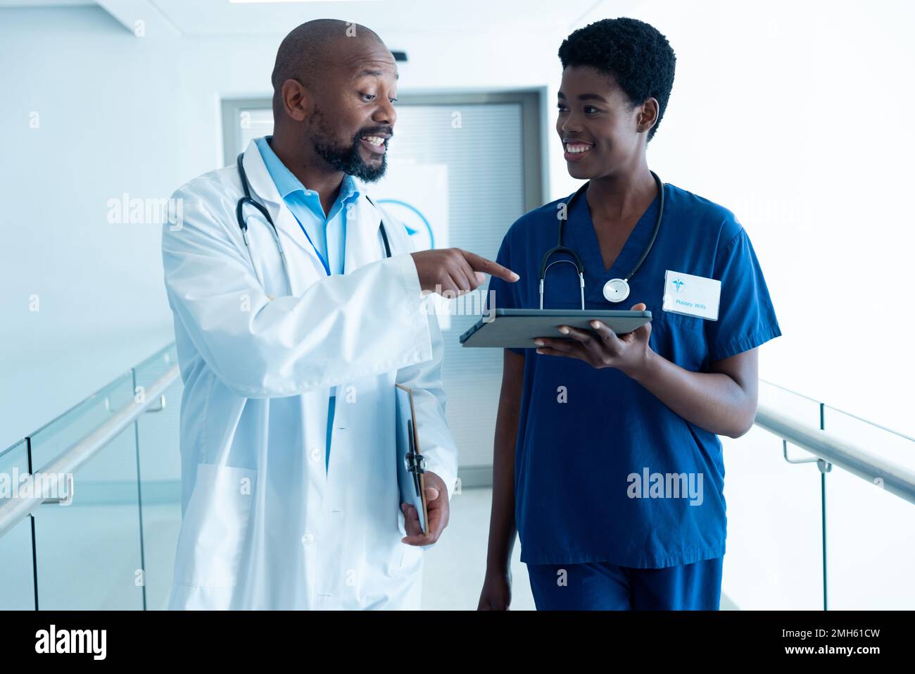 Smiling african american male and female doctor using tablet, talking ...