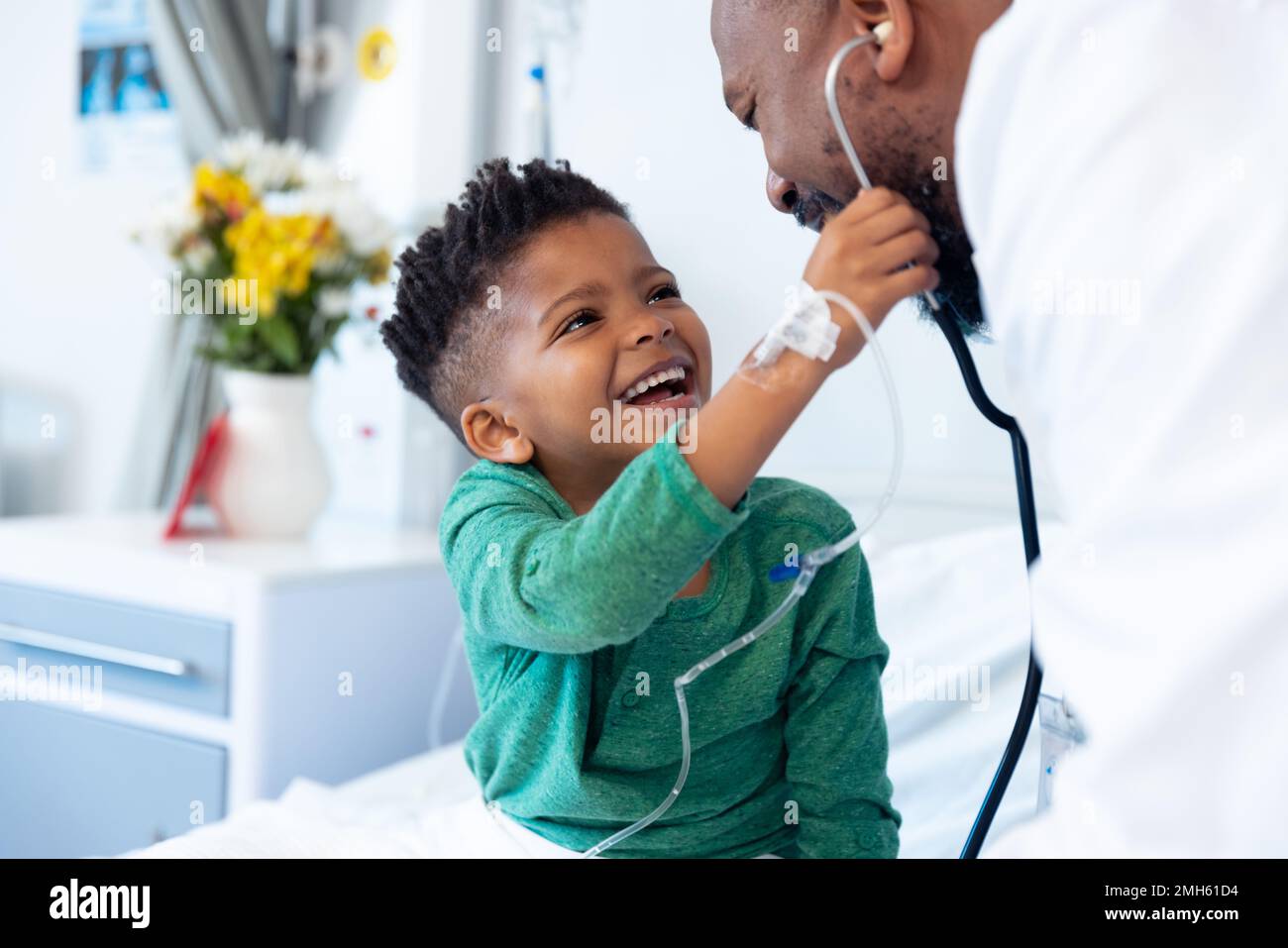 Laughing african american boy patient taking male doctor's stethoscope ...