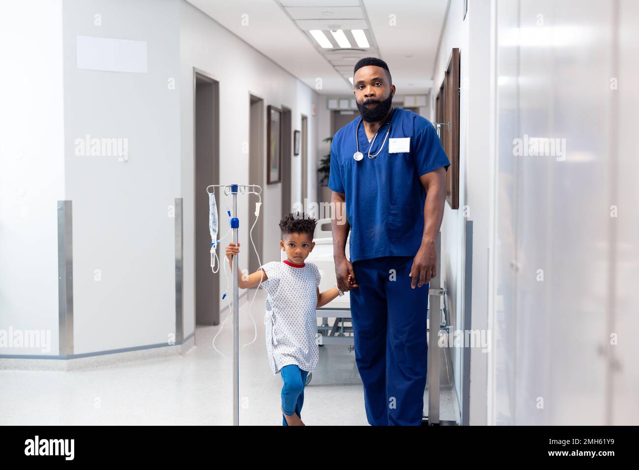 African american male doctor holding hand of boy patient with drip in ...