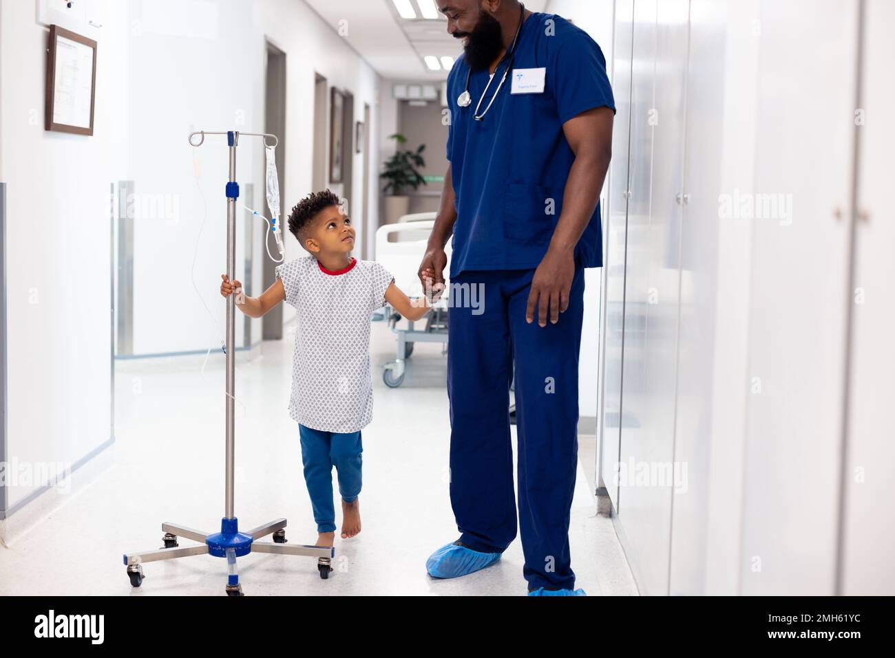 Happy african american male doctor holding hand of boy patient with ...