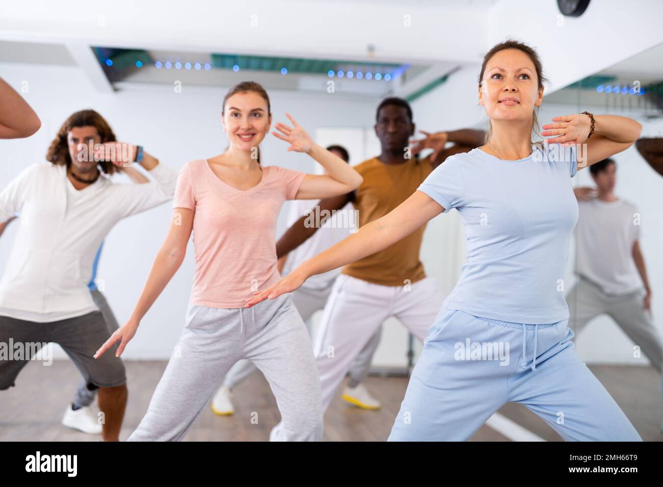 Men and women dancing synchronous group choreography in dance hall ...
