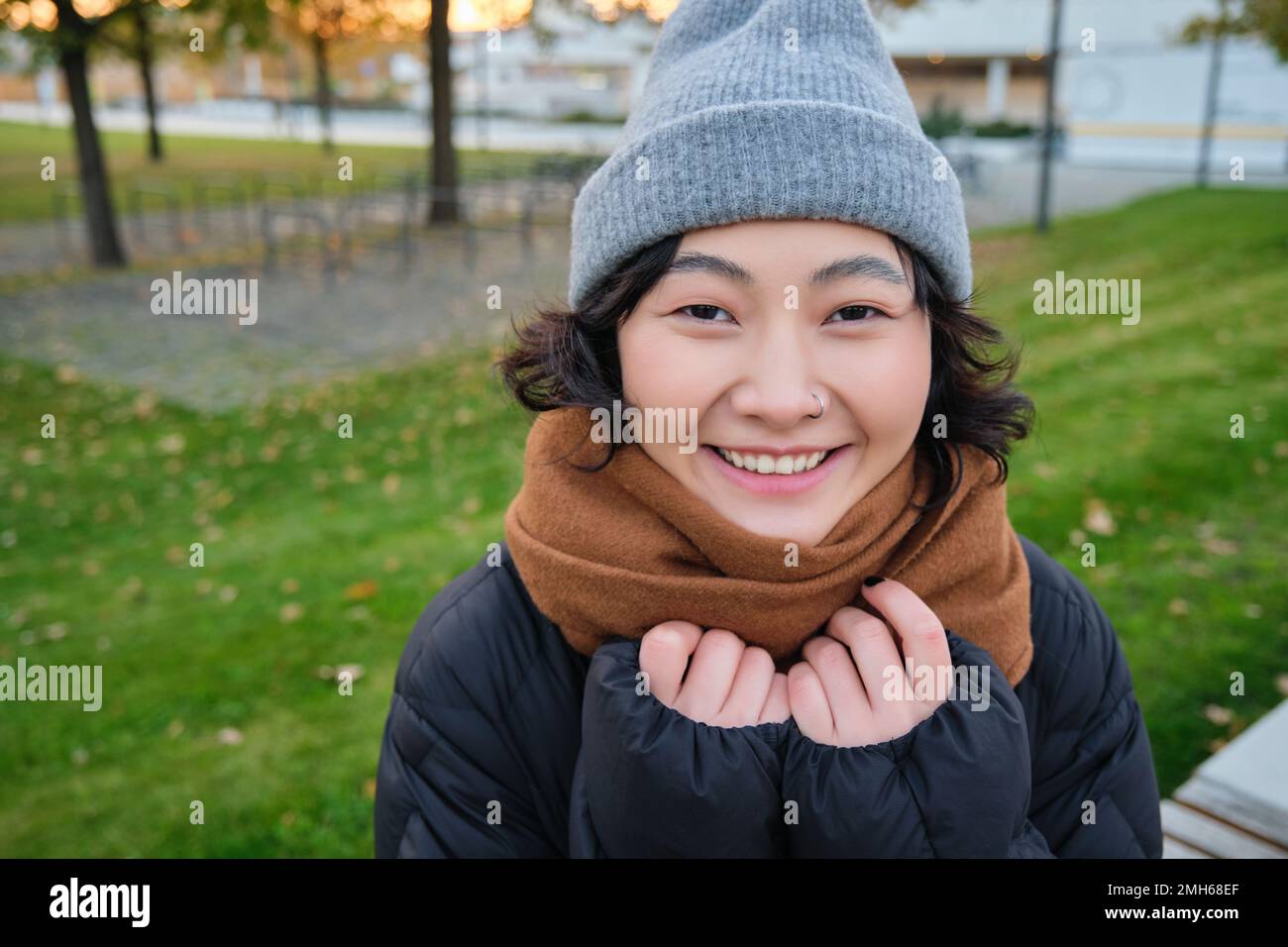 Portrait of cute asian girl in hat and scarf, walks around town in ...