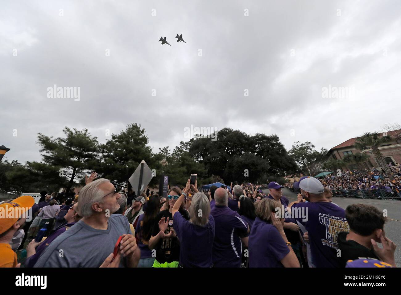 Fighter jets fly in formation overhead as fans wait for the start of a ...