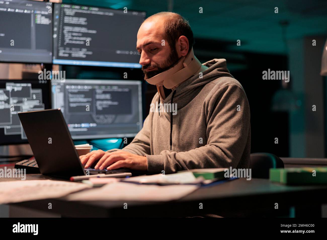 Male web developer with medical neck collar programming code in office, feeling sick after ...