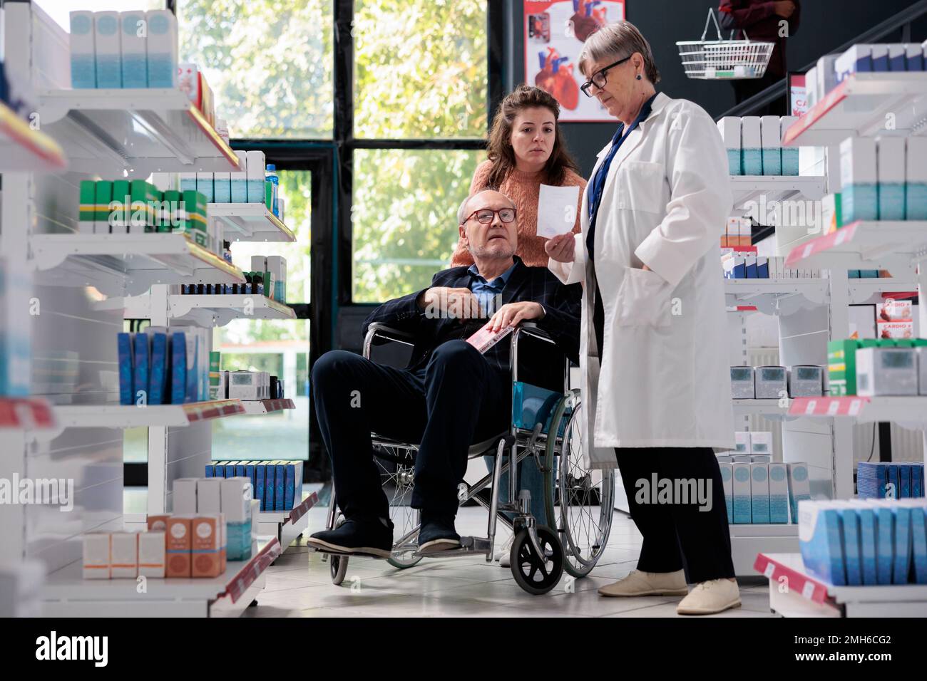 Senior pharmacist discussing health care treatment with disabled ...